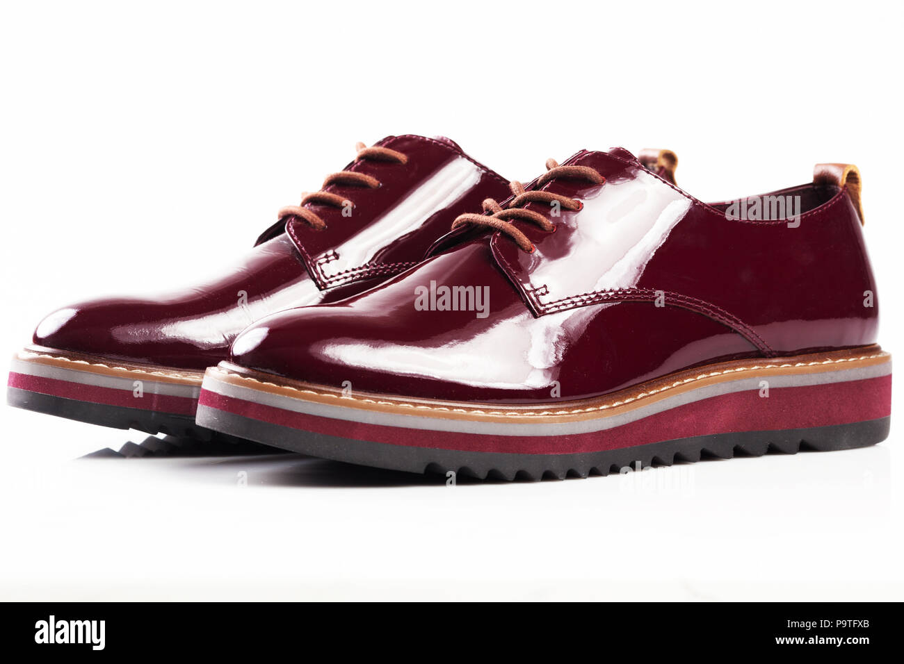 Deep red shiny pair of shoes on a white background Stock Photo - Alamy