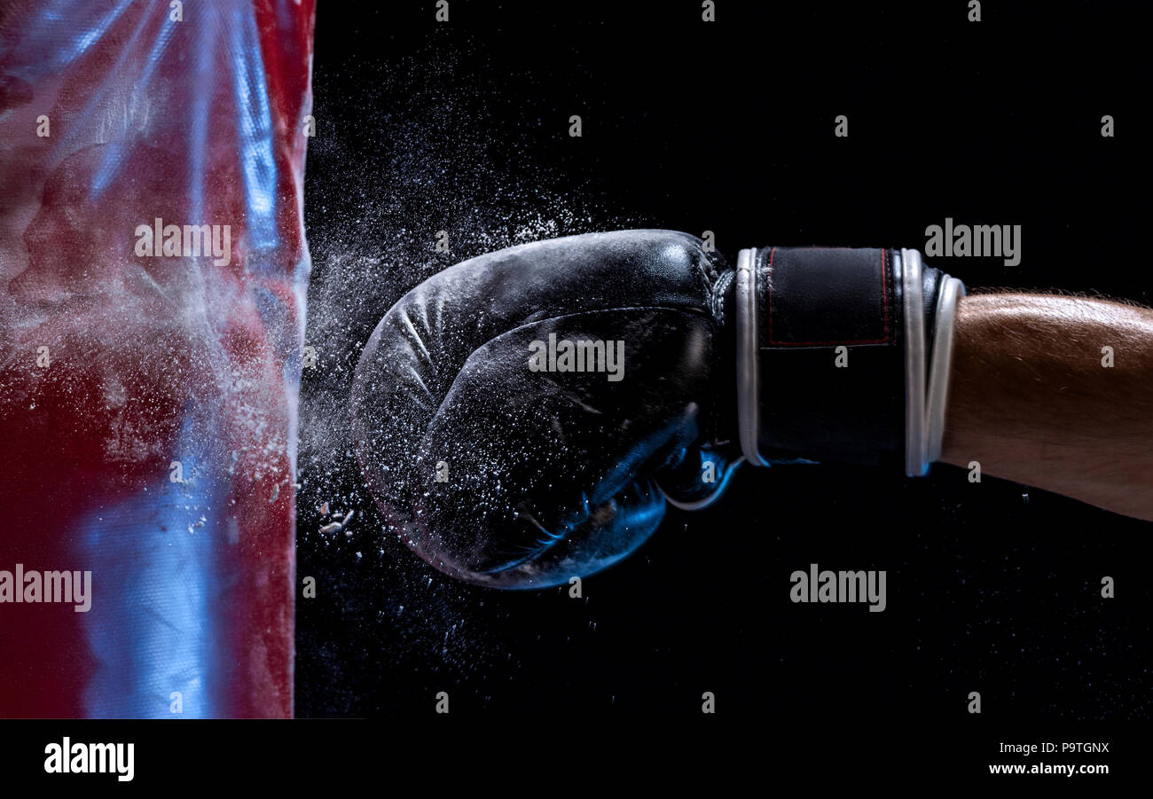 Close-up hand of boxer at the moment of impact on punching bag over ...