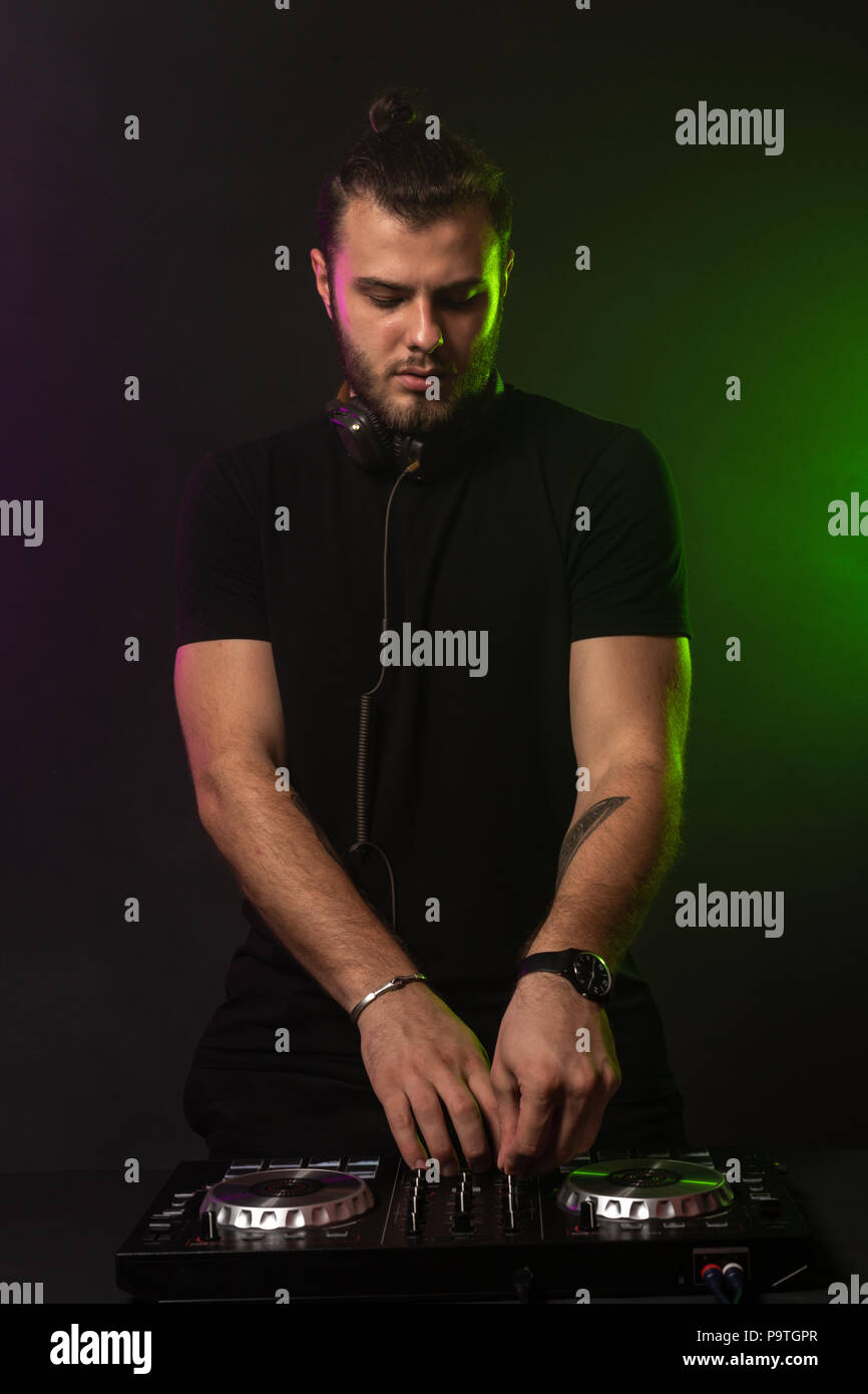 DJ playing music at mixer on colorful foggy background. A fashionable ...