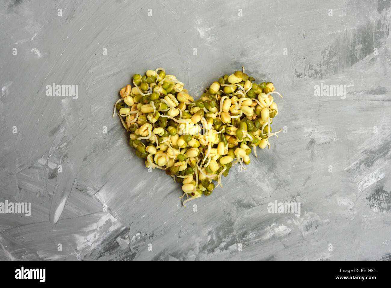 Heart shape made from mung beans with sprouts on grey concrete ...