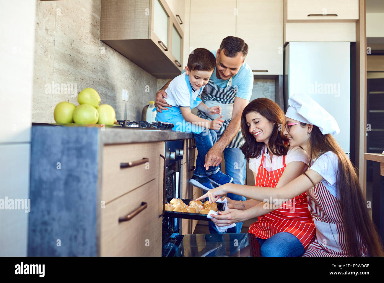 Happy family bakes buns in the oven in the kitchen Stock Photo - Alamy