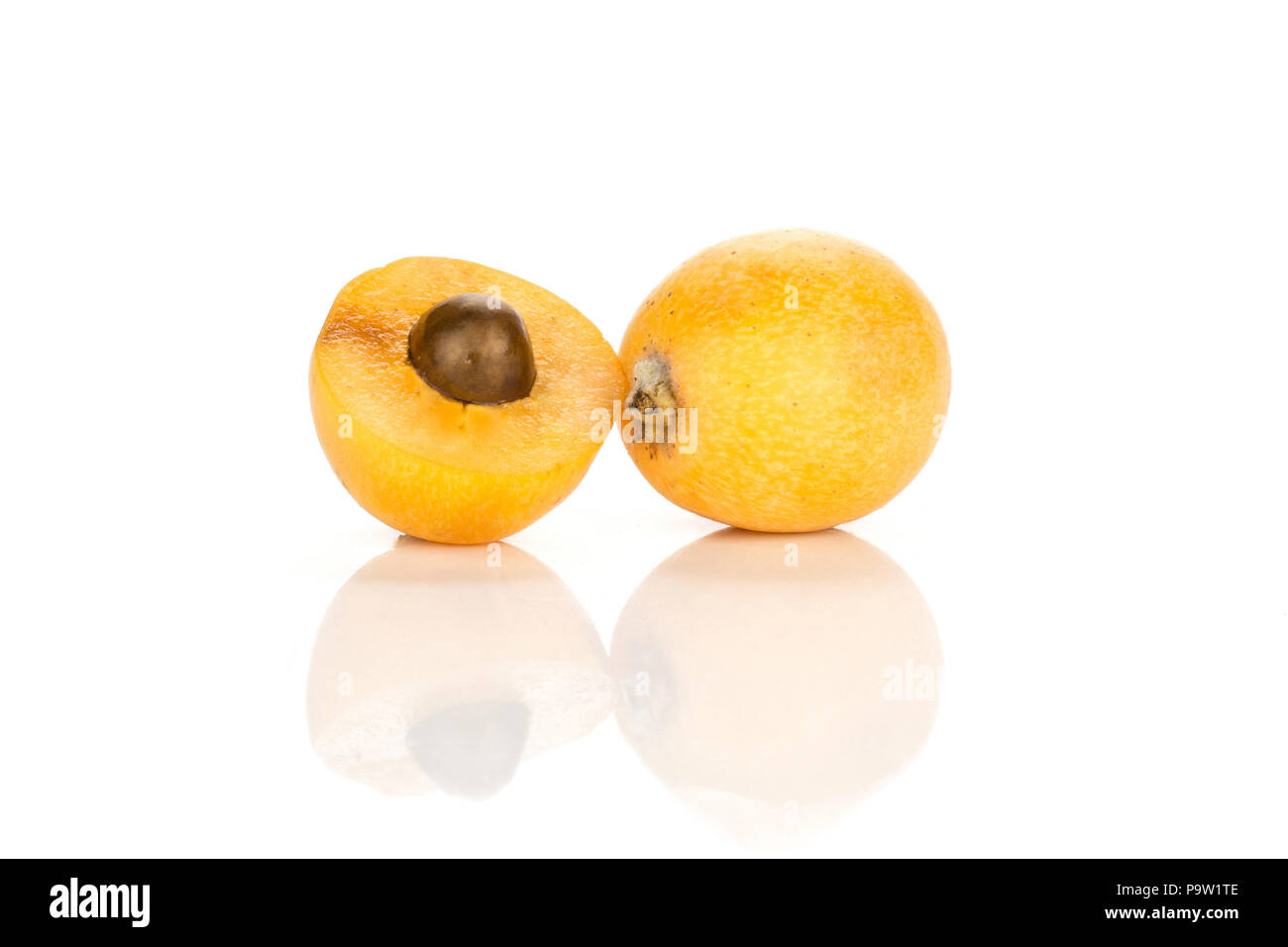 One fresh orange Japanese loquat and sliced half with a seed inside ...