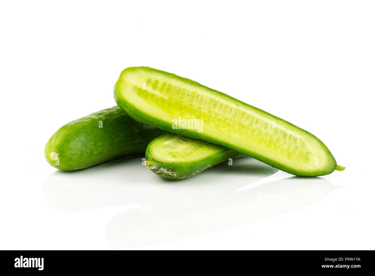 One fresh green mini cucumber with two section halves isolated on white ...