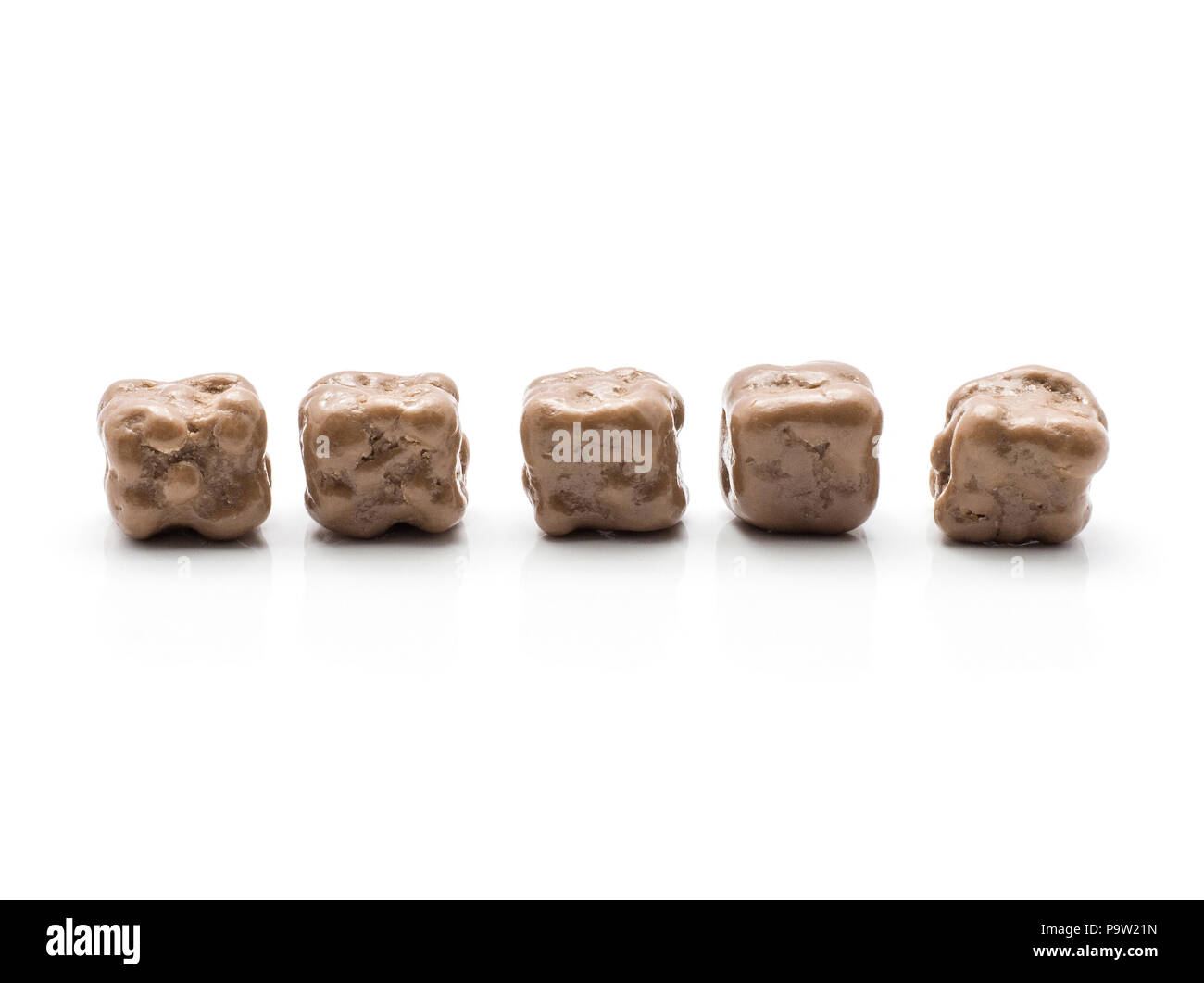 Five milk chocolate coconut cubes in row isolated on white background ...
