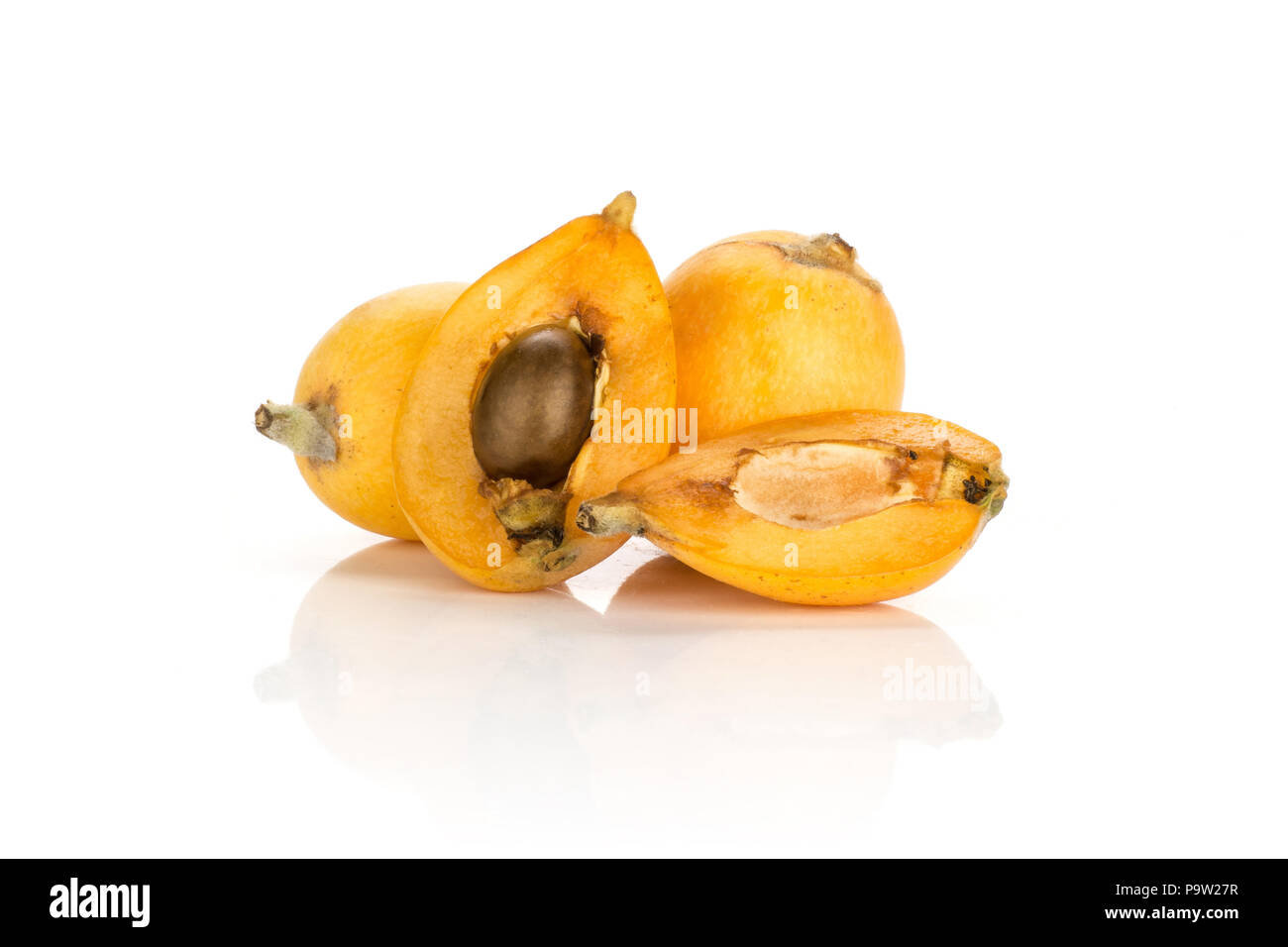 Three fresh orange Japanese loquats one cut in two halves with a seed ...