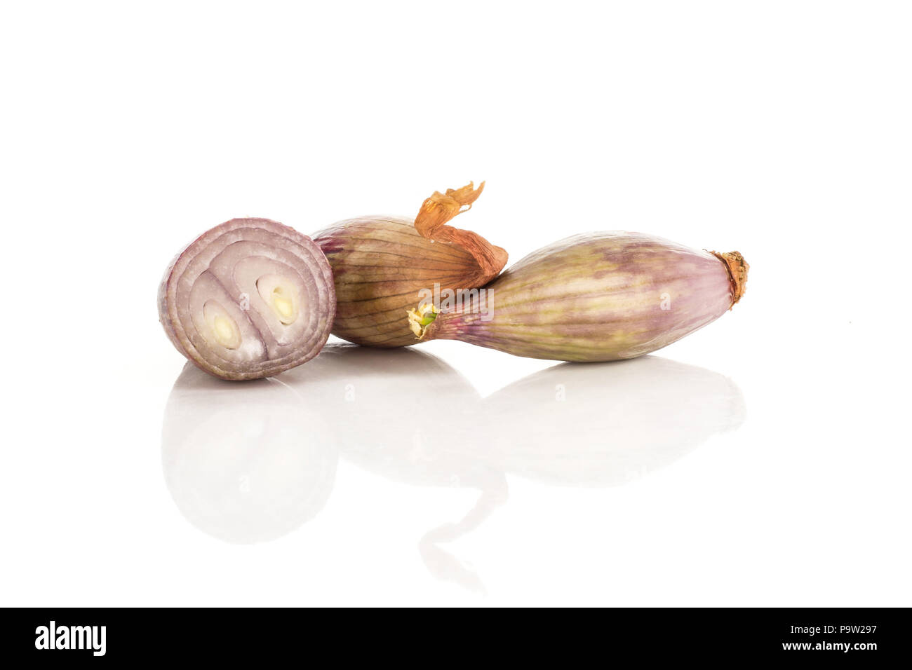 Two peeled green purple shallots and one sliced half isolated on white ...