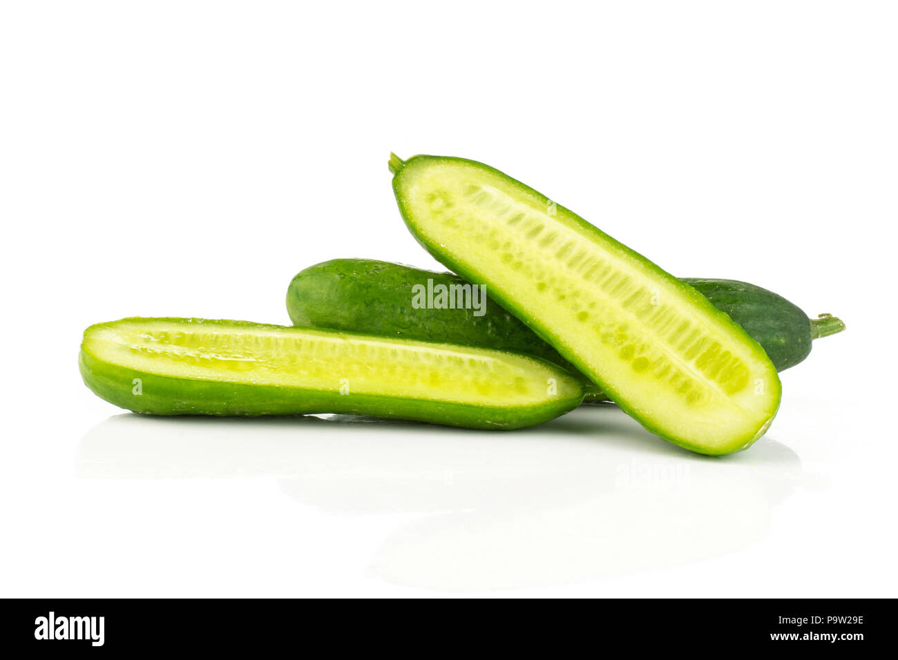 One fresh green mini cucumber and two section halves isolated on white ...