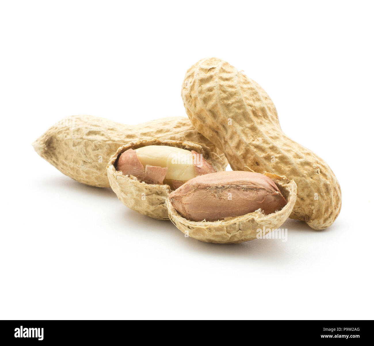 Three peanuts one broken isolated on white background two raw seeds in ...
