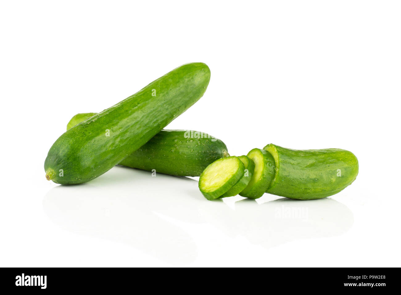 Two fresh green mini cucumbers and sliced half with three slices ...