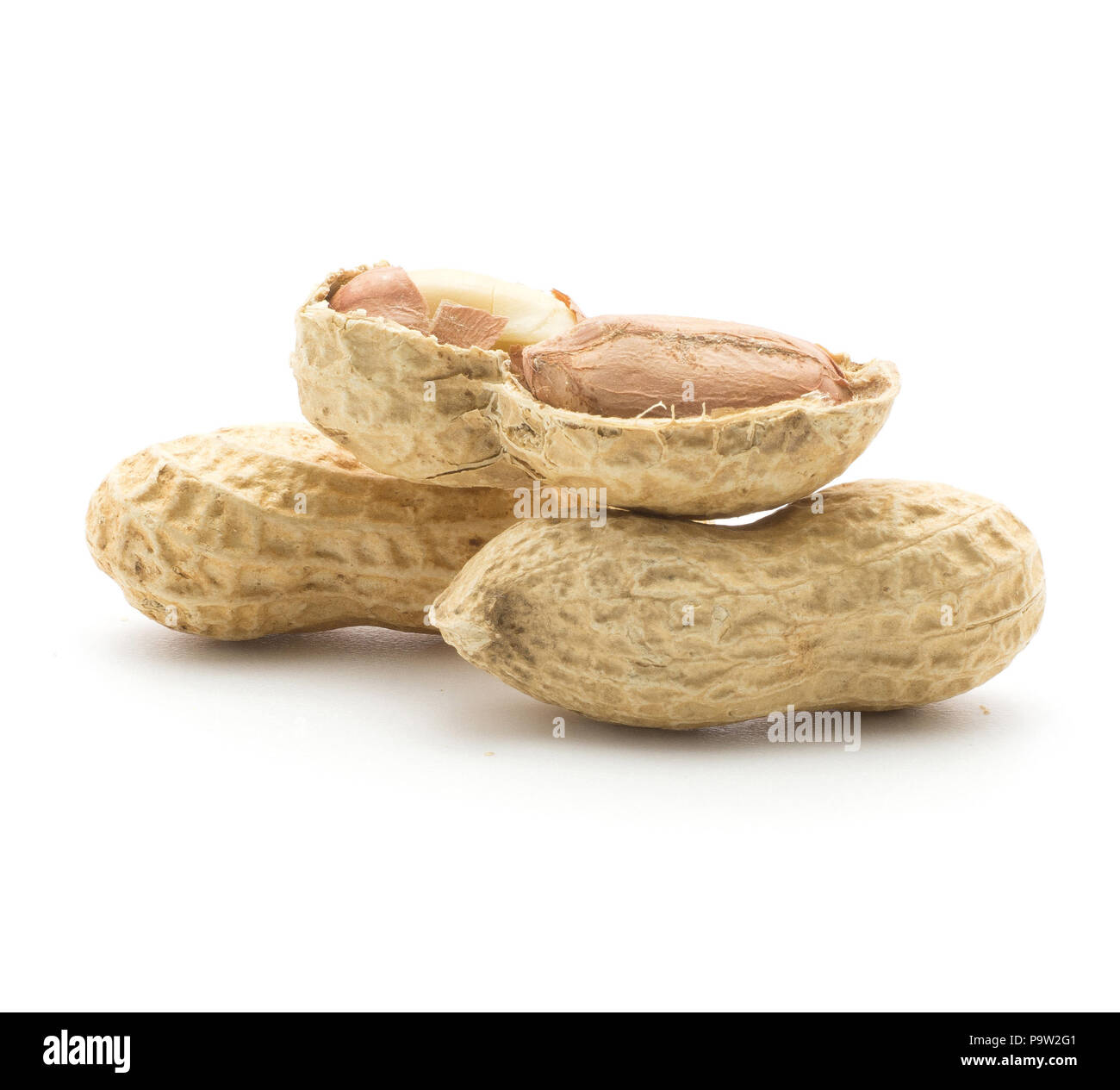 Three peanuts one open isolated on white background two raw seeds in ...