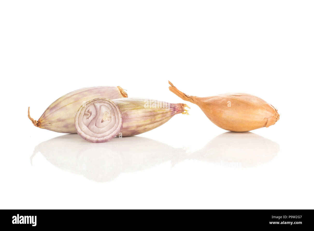 Two peeled shallots one in a husk and a ring slice isolated on white ...