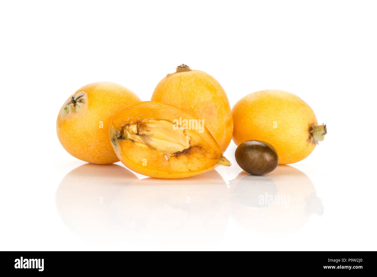 Fresh orange Japanese loquats three whole one half with separated seed ...