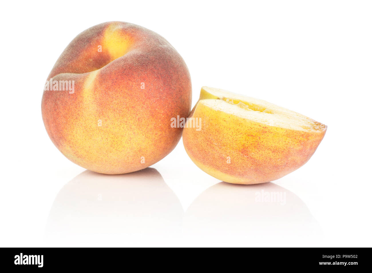 One yellow peach with a cut half without drupe isolated on white ...