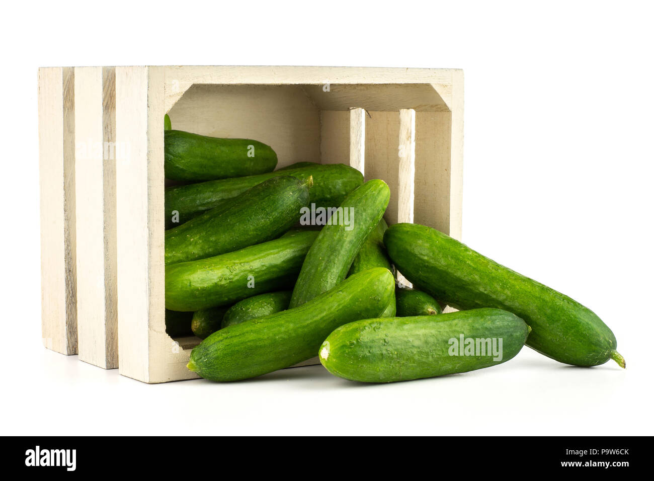 Fresh green mini cucumbers out a wooden box isolated on white ...
