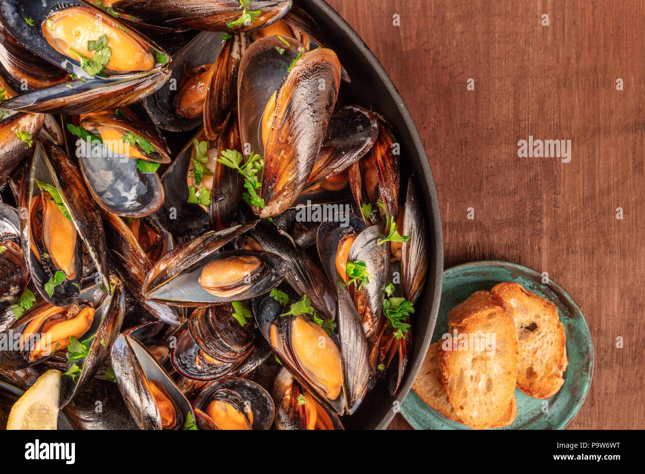 A full skillet of marinara mussels, shot from above on a dark rustic ...