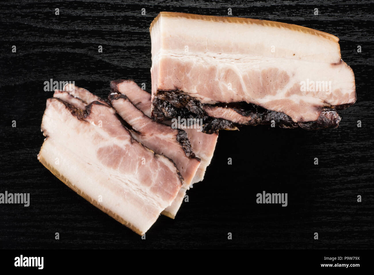 Group of three slices one piece of english bacon flatlay on black wood ...