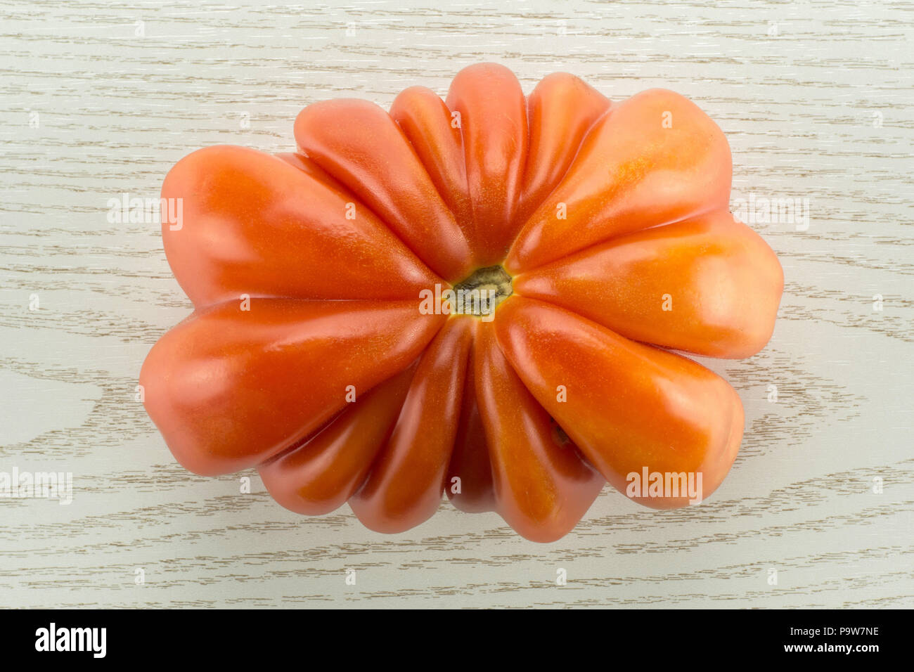 Beef tomato (flower shape) top view isolated on grey wood background ...