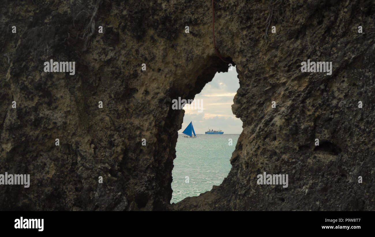 Sailing boat view through a hole in the rock. Sailing ship yachts with ...