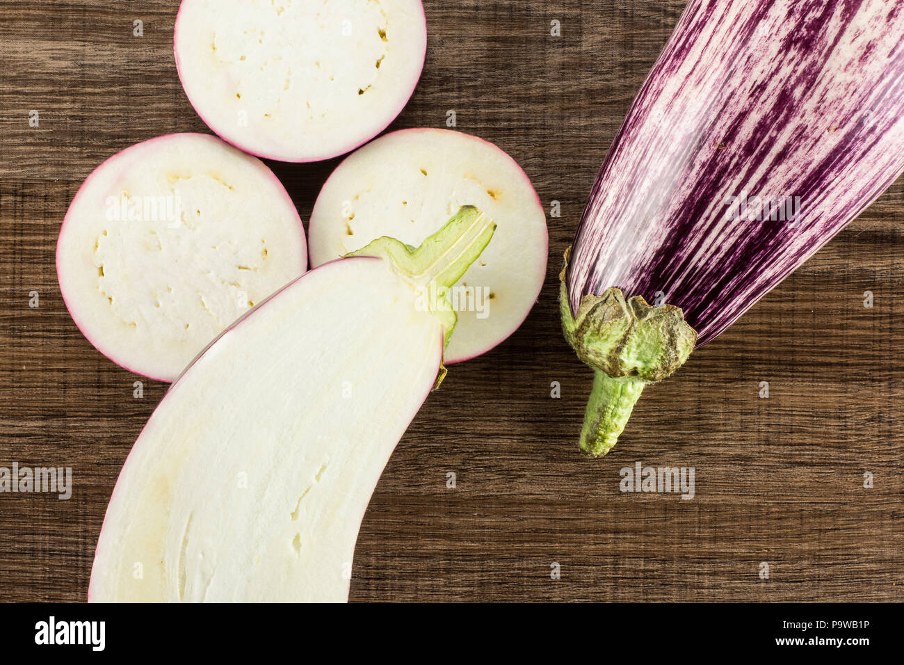 Striped purple eggplants set top view isolated on brown wood background ...