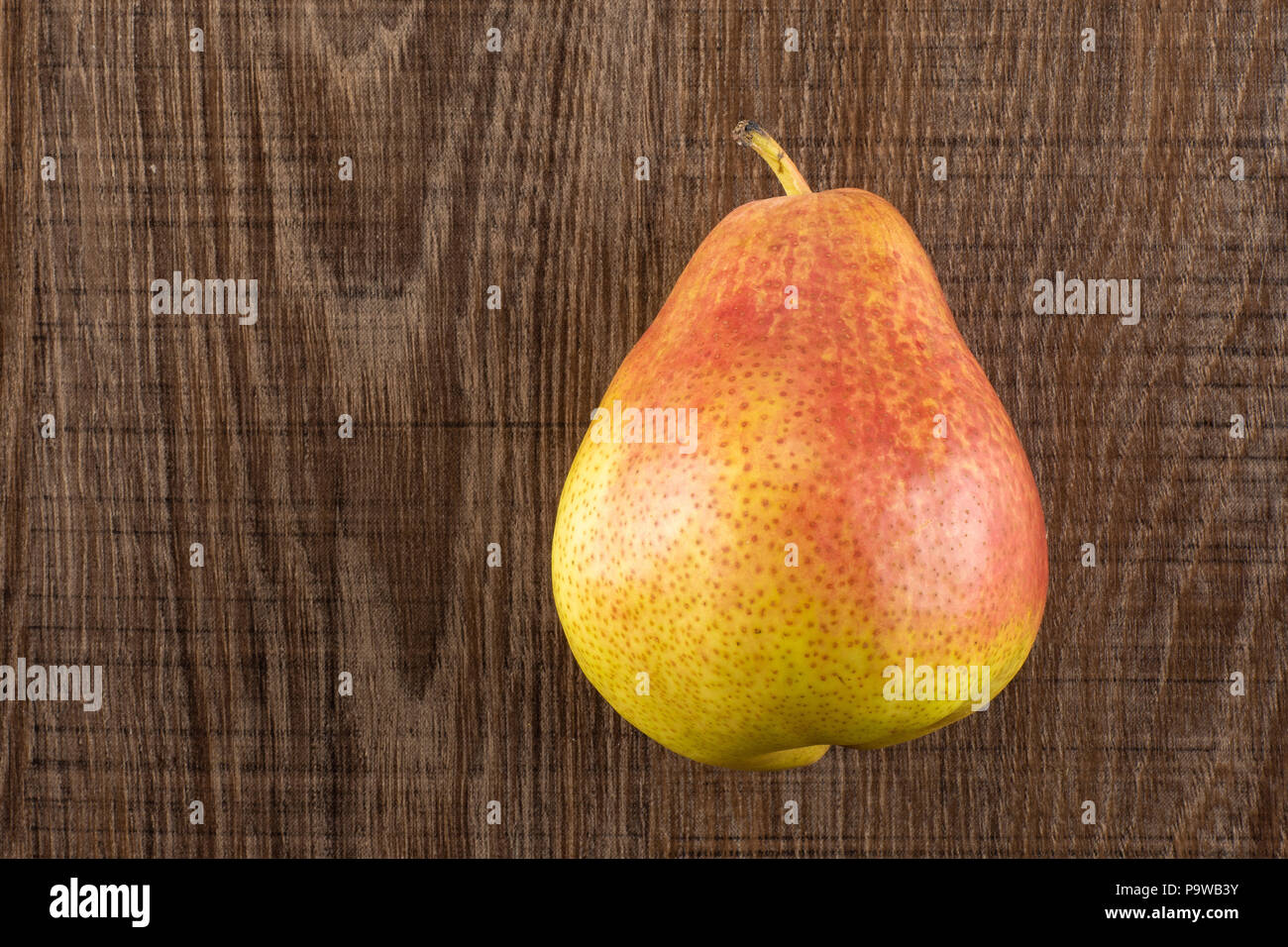 One whole fresh red pear forelle variety flatlay on brown wood Stock ...