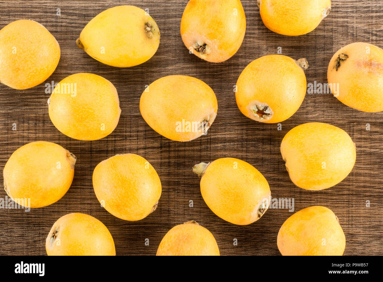 Fresh orange Japanese loquats flatlay isolated on brown wood background ...