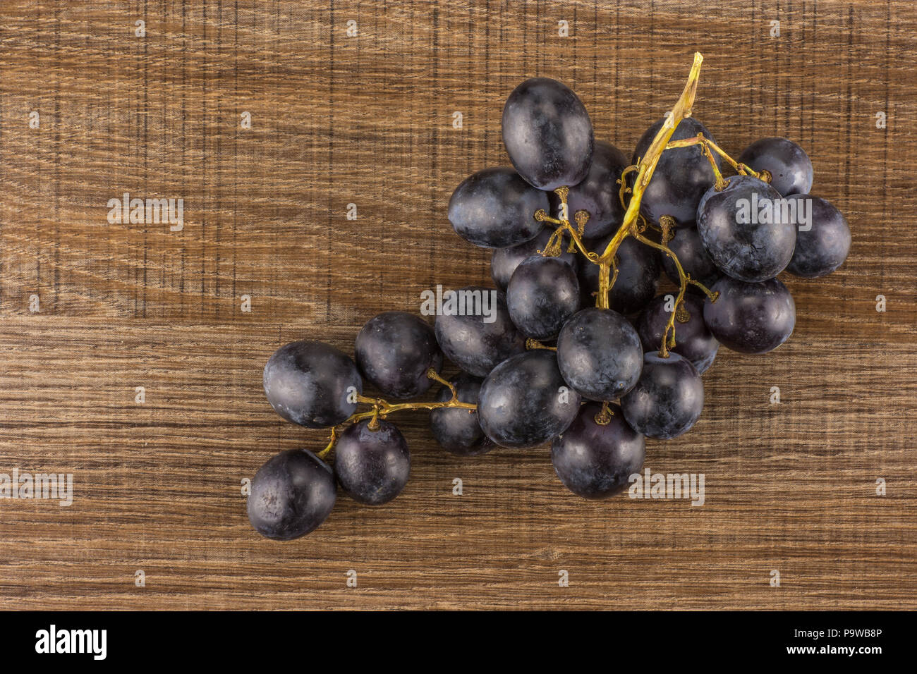 Black grape cluster (autumn royal variety) table top isolated on brown ...