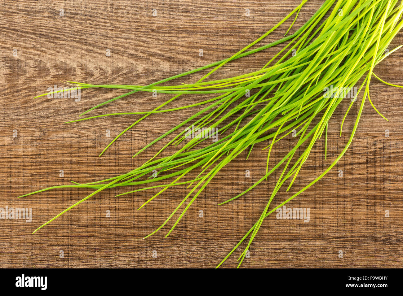 Fresh chives table top isolated on brown wood background grass slender ...
