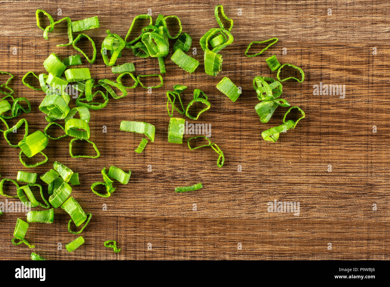 Fresh green spring onion red scallion variety flatlay on brown wood ...