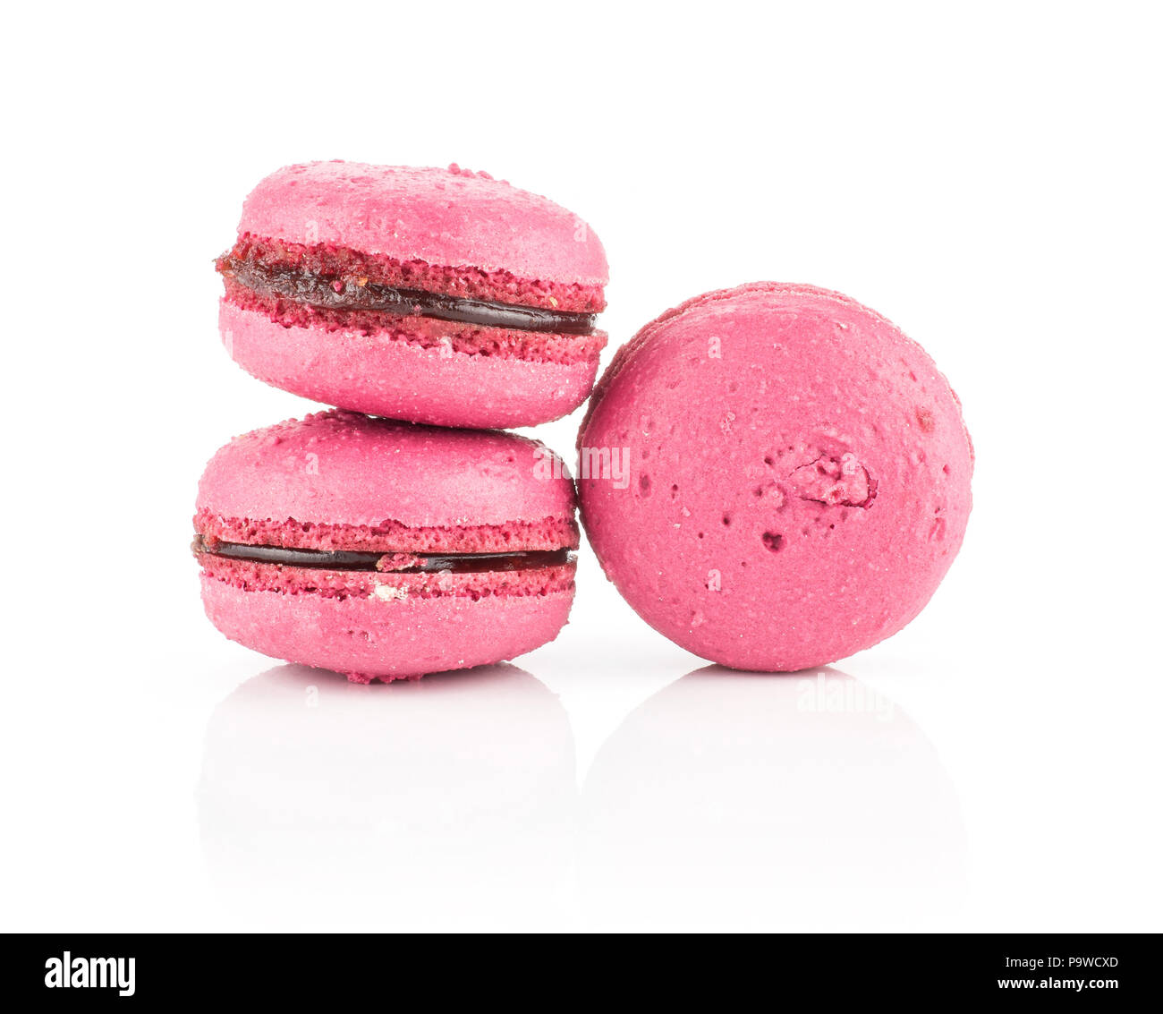 Three pink French macarons with raspberry jam isolated on white ...