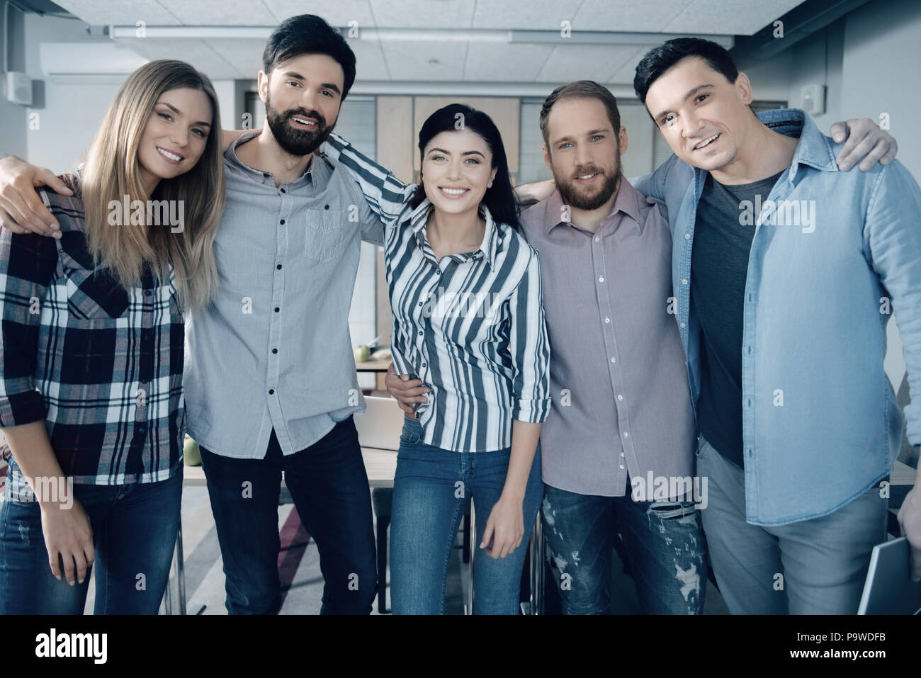 Team spirit. Smiling young group of colleagues bonding to each other ...