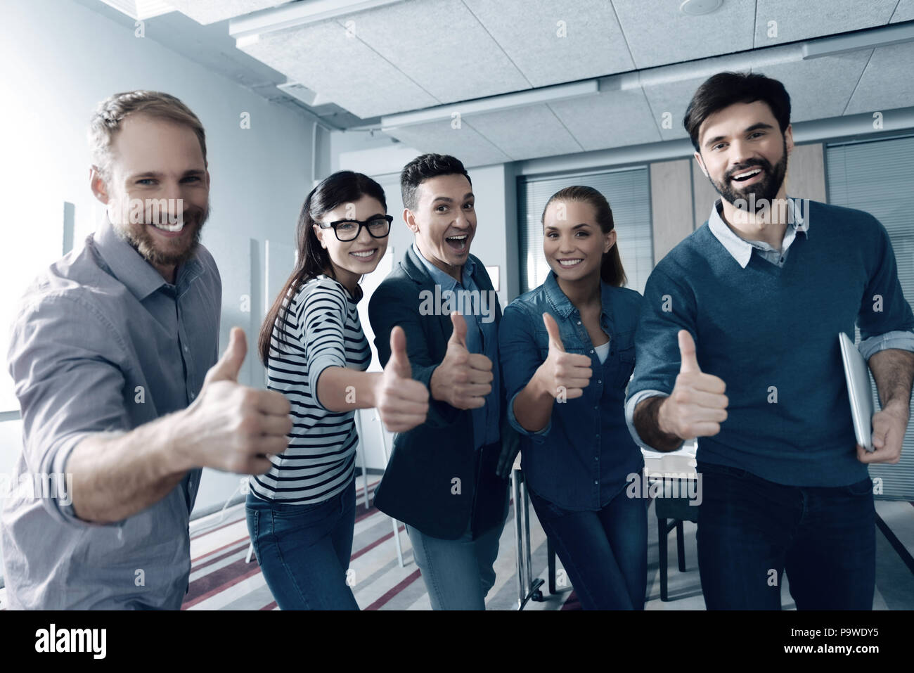 Only positive emotions. Cheerful smiling young colleagues standing in ...