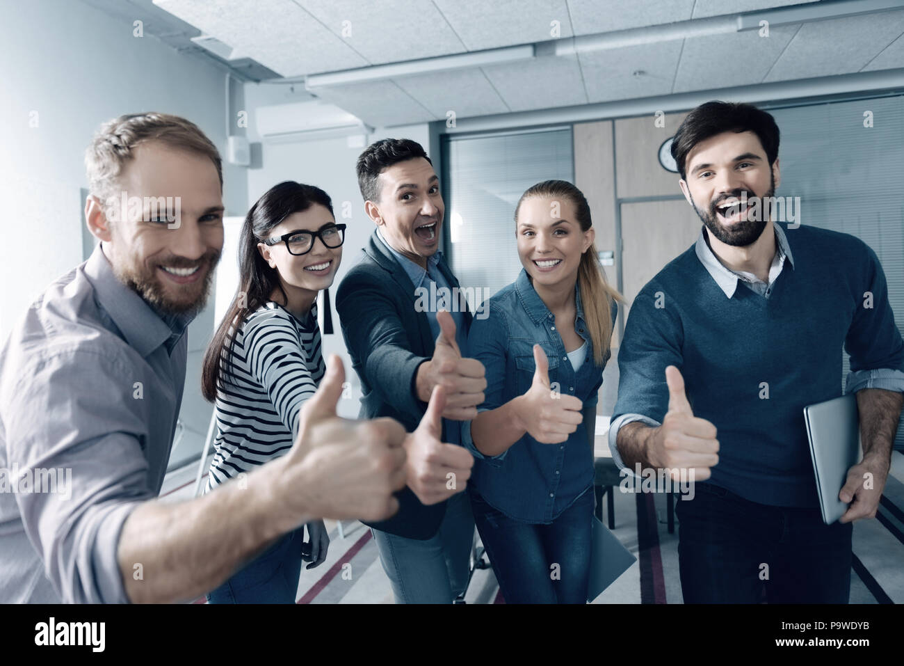 Stay optimistic. Positive smiling colleagues smiling and standing in ...