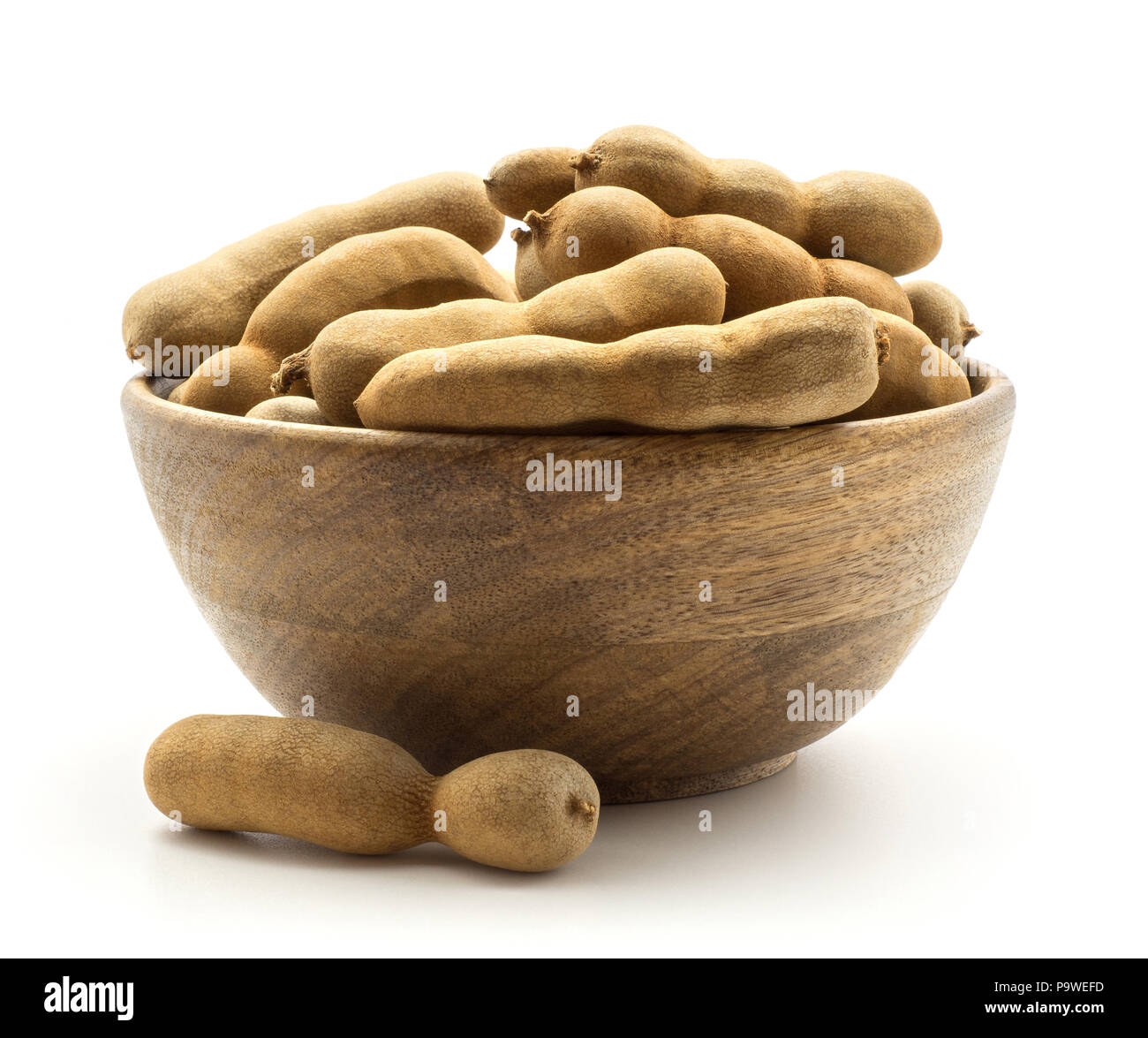 Tamarind Indian dates in a brown wooden bowl isolated on white ...