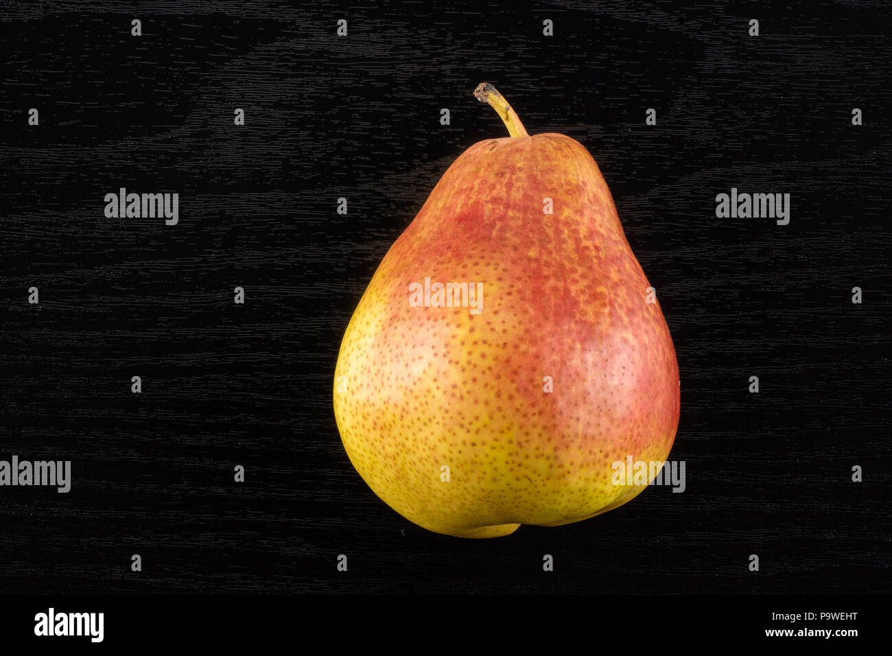 One whole fresh red pear forelle variety flatlay on black wood Stock ...
