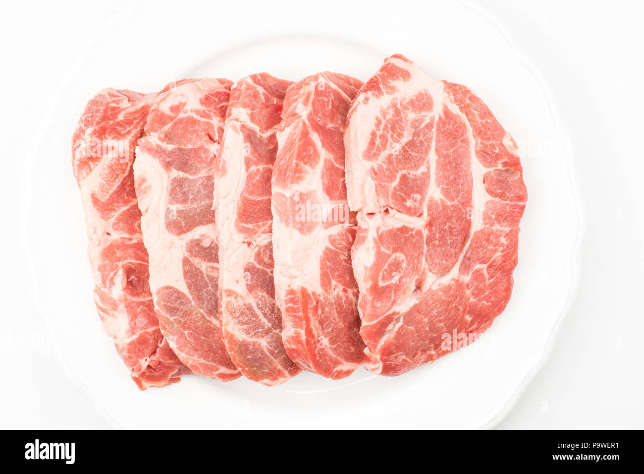 Raw pork neck meat cuts on a plate top view isolated on white ...