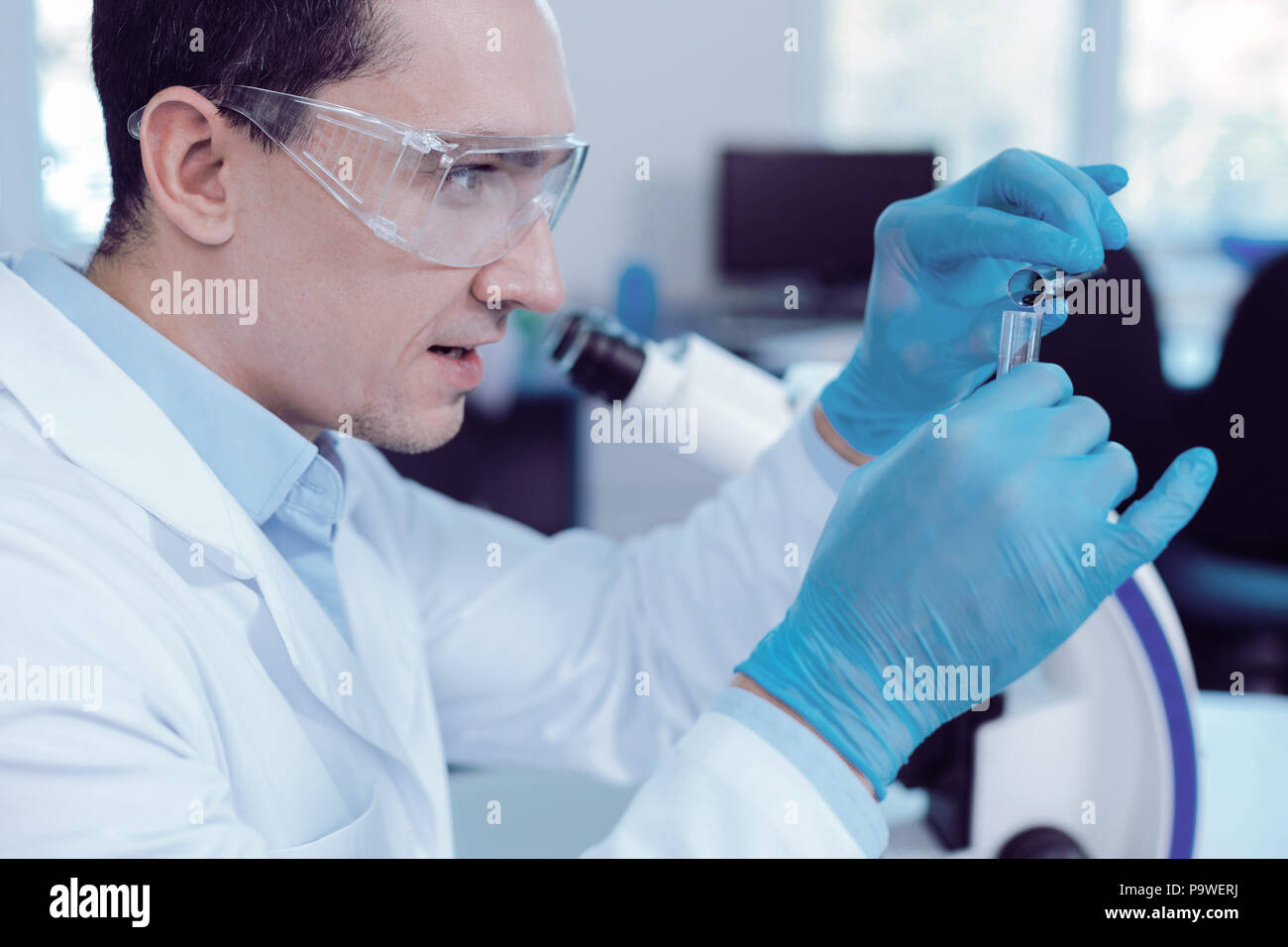 Biological discovery. Smart nice handsome scientist holding a test tube ...