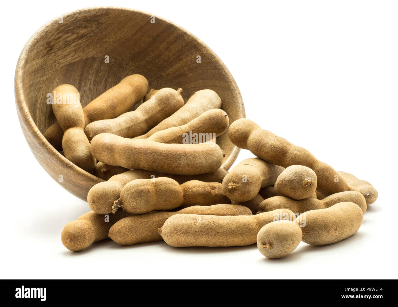 Tamarind Indian dates out a brown wooden bowl isolated on white ...