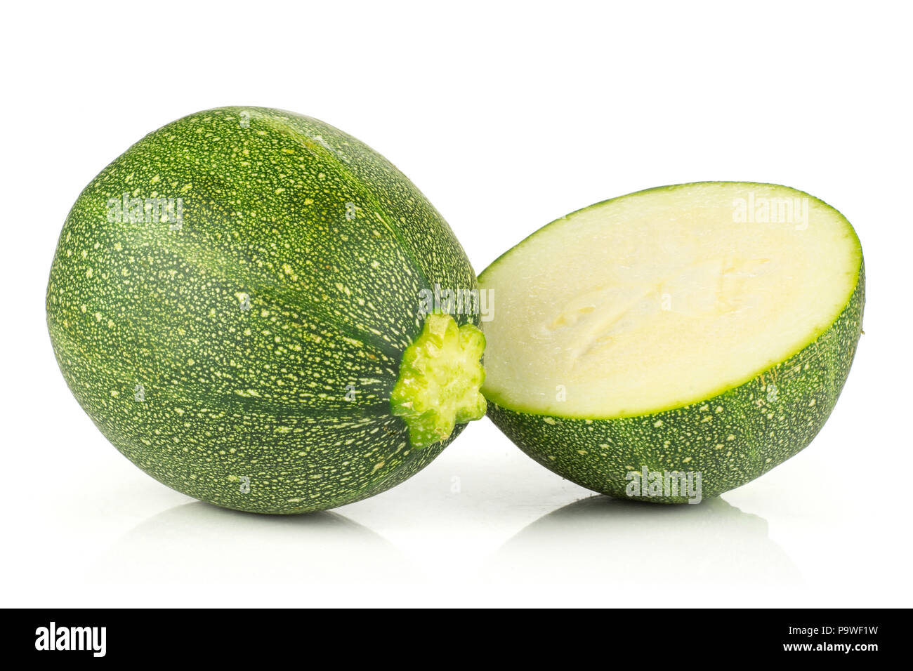 One round zucchini with one section half isolated on white background ...