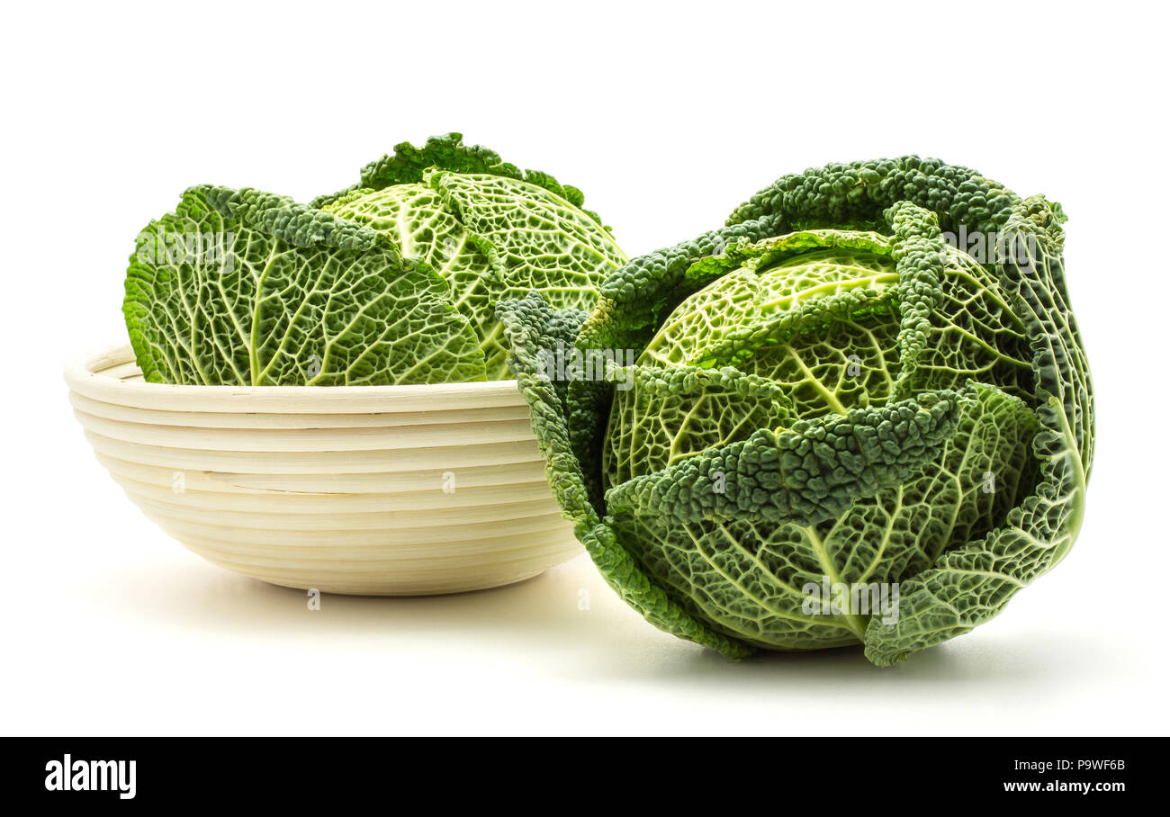 Two savoy cabbages in a wicker basket isolated on white background ...