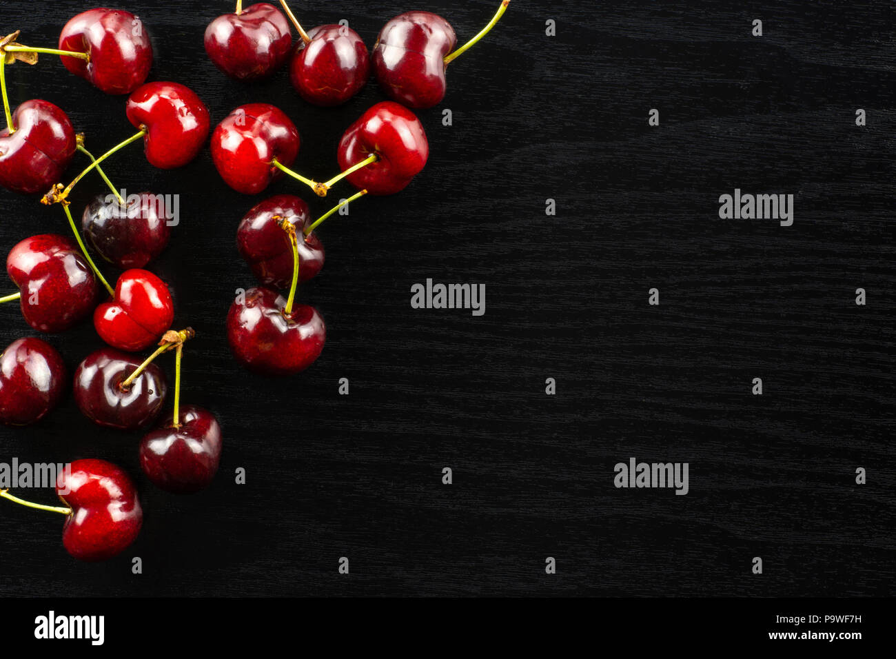 Sweet bright red cherry left upper corner flatlay on black wood Stock ...