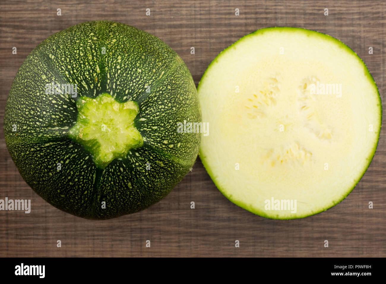 One round zucchini with cross section half flatlay on brown wood fresh ...