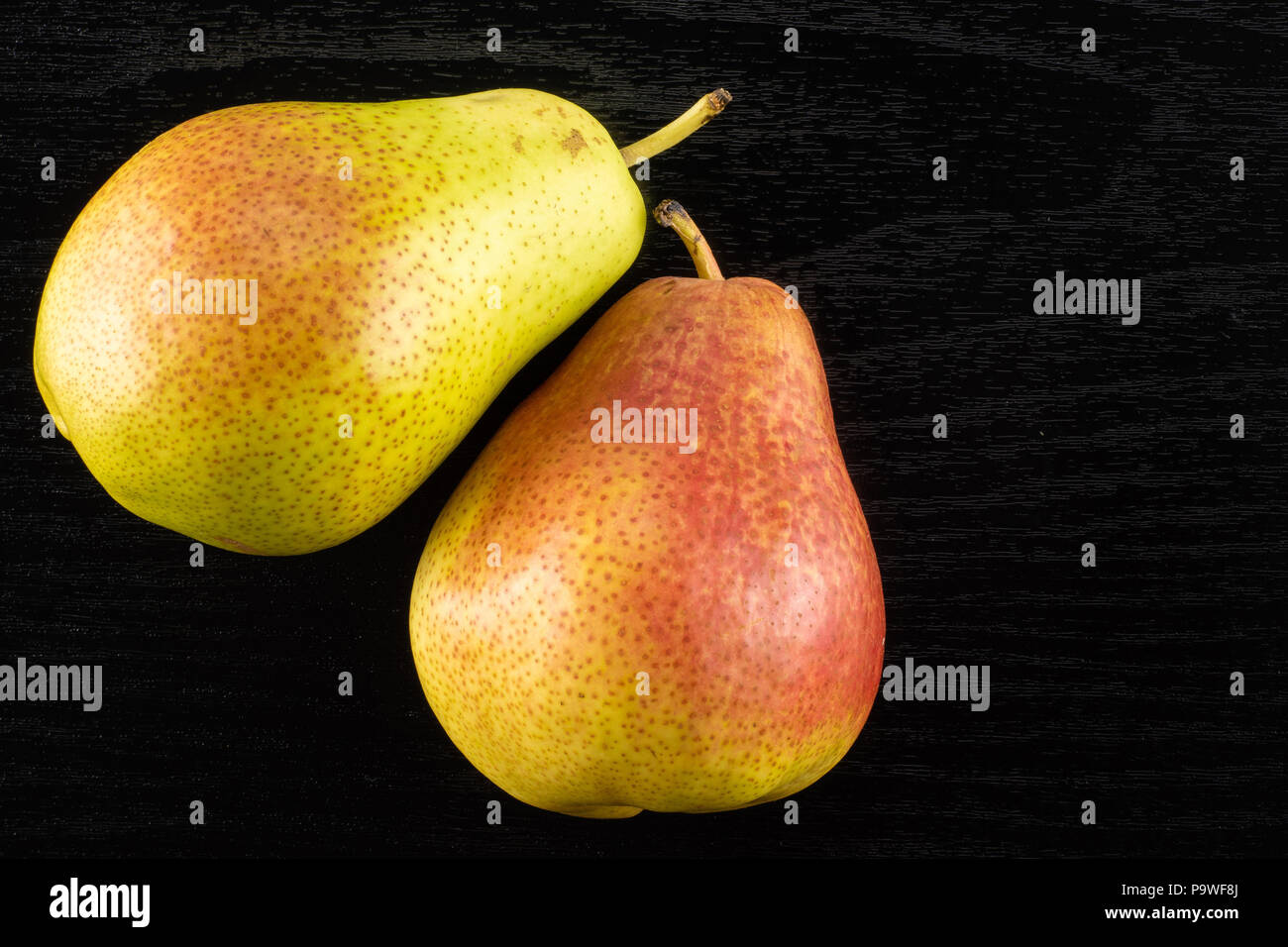 Group of two whole fresh red pear forelle variety flatlay on black wood ...