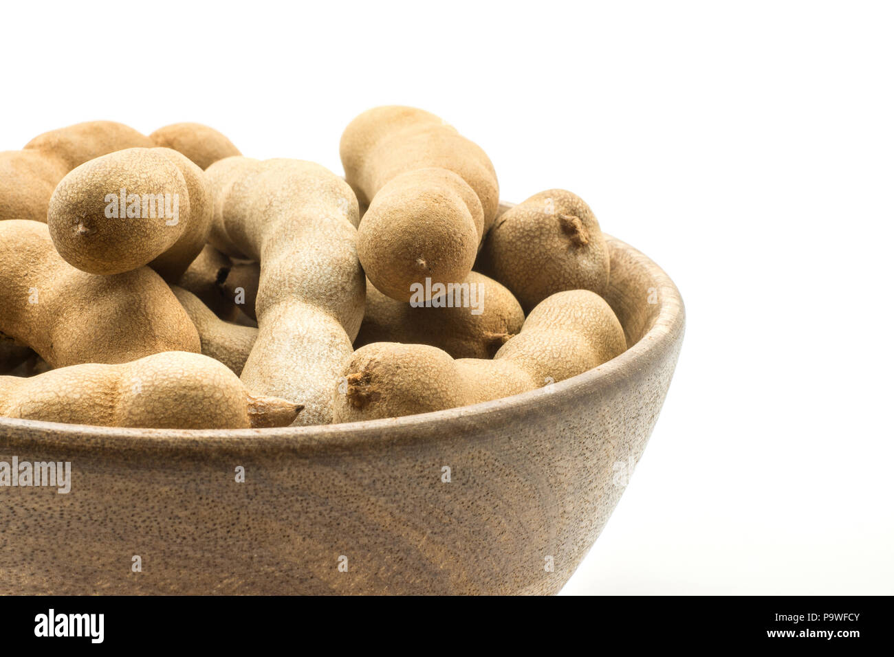 Indian dates tamarind in a wooden bowl isolated on white background ...