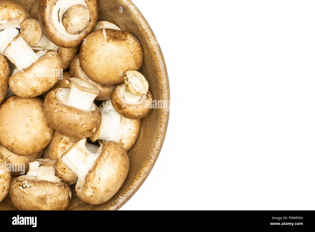 Fresh brown champignons in a wooden bowl top view isolated on white ...