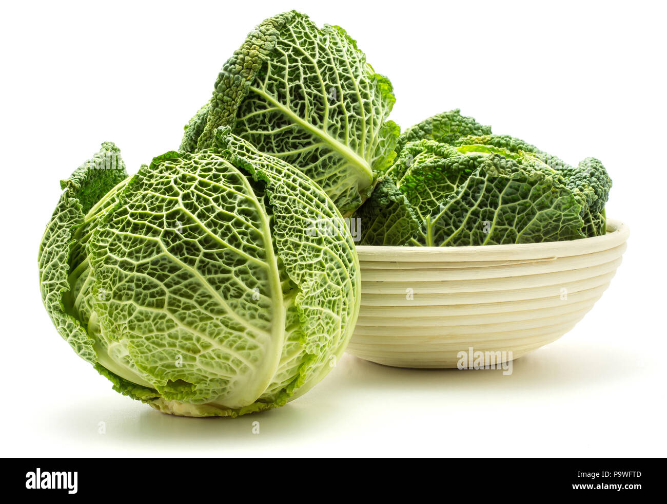 Three savoy cabbages in a rattan bowl isolated on white background ...
