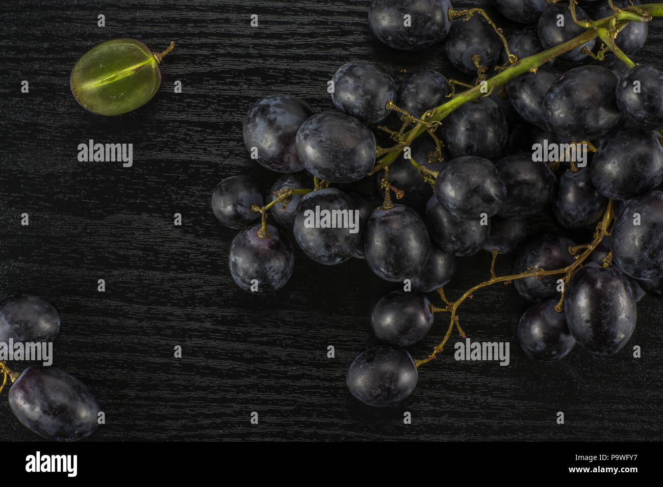Black grape clusters (autumn royal variety) with one sliced berry table ...