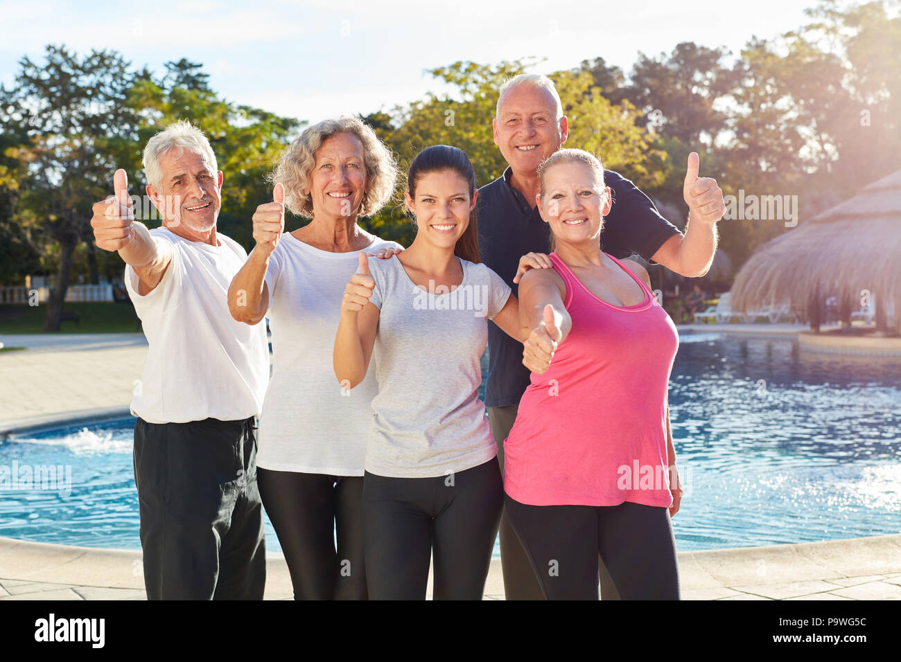 Group of seniors in a spa vacation at the pool is happy with thumbs up ...
