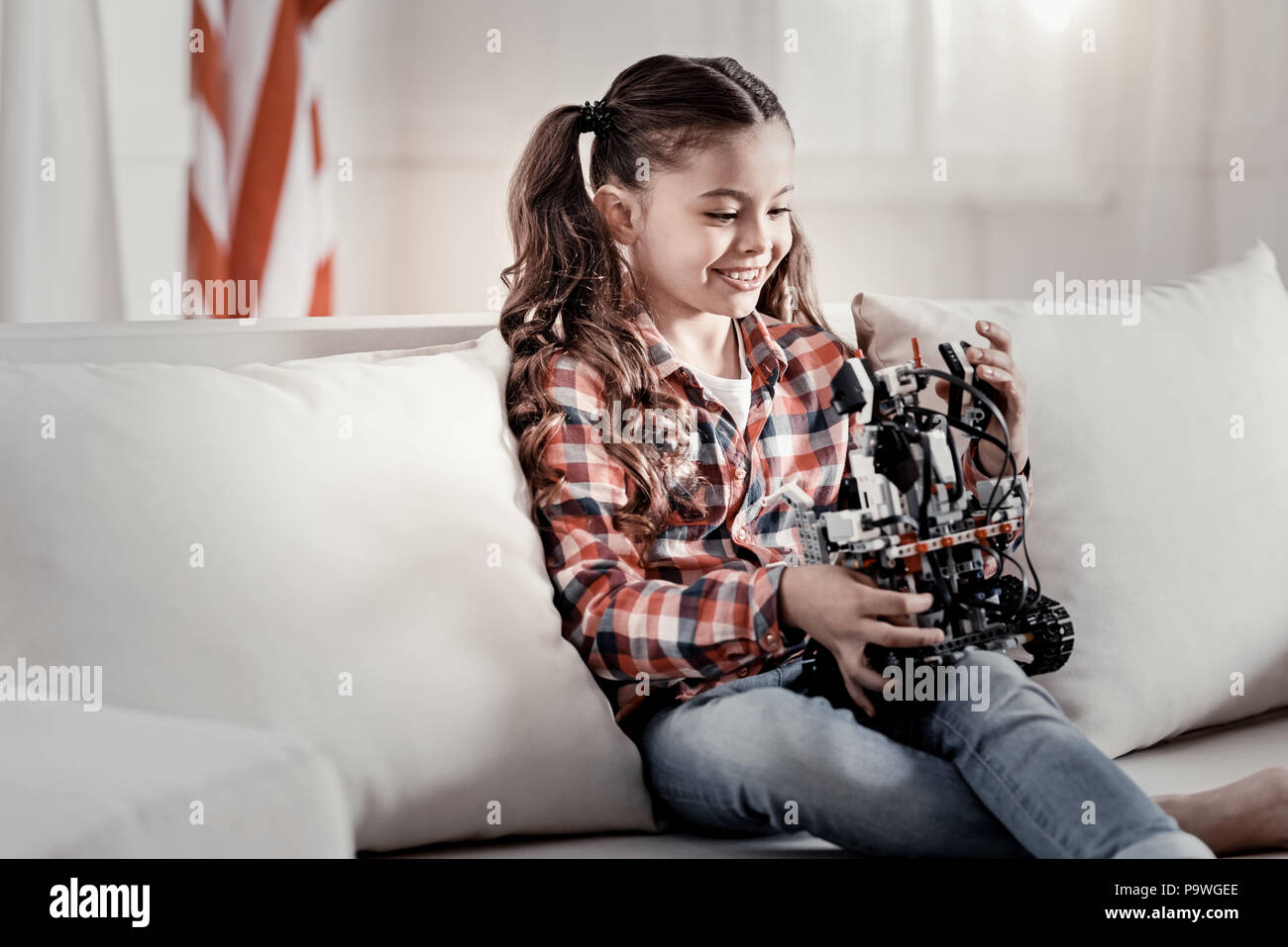 Cool robot. Sunny brunette little girl holding her robot toy while ...