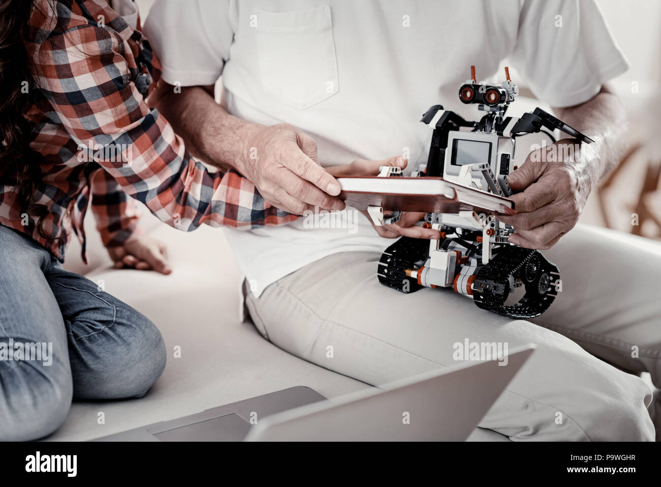 Grandfather demonstrating mechanical toy robot functions by giving it ...