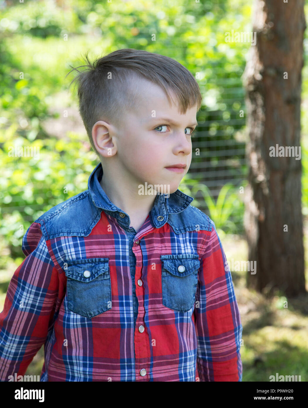 six-year-old boy looks askance at the lens in the spring garden Stock ...